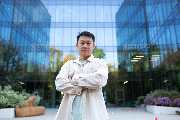 Portrait of a serious young handsome successful male Asian programmer ...