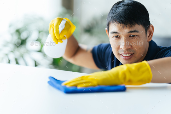 Smiling attractive asian young man cleaning his house with rag and ...