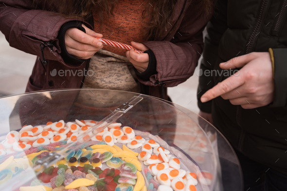 Hands of adult people choosing sweets at candy bar in street market at ...