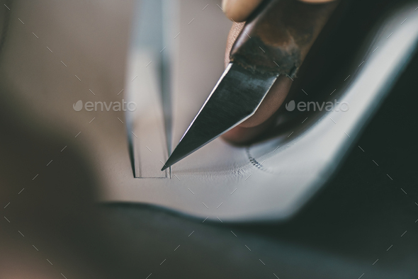 close-up partial view of shoemaker cutting sole outline with knife ...