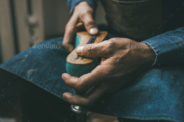 partial view of shoemaker holding plastic boot workpiece and working ...
