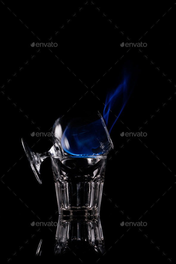 close up view of alcohol sambuca drink burning in glass on black ...
