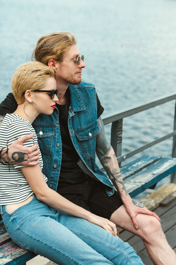 side view of boyfriend with tattoos and stylish girlfriend hugging on ...