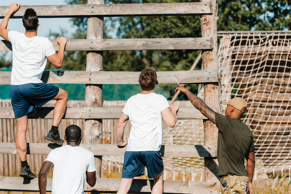 tactical instructor examining multiracial soldiers during obstacle run ...