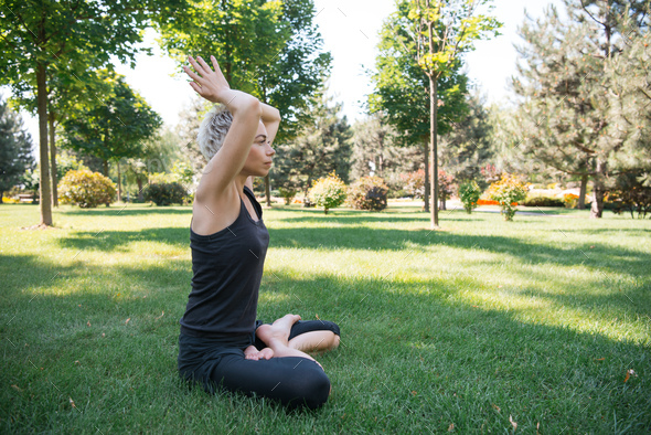 side view of woman practicing yoga in lotus pose with raised hands ...