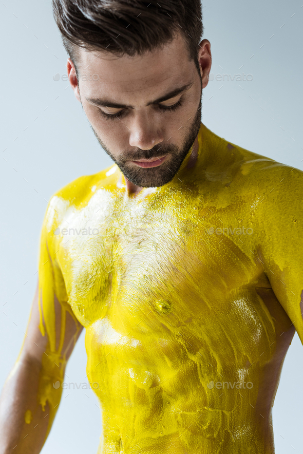 Man looking at his body painted yellow isolated on white background ...