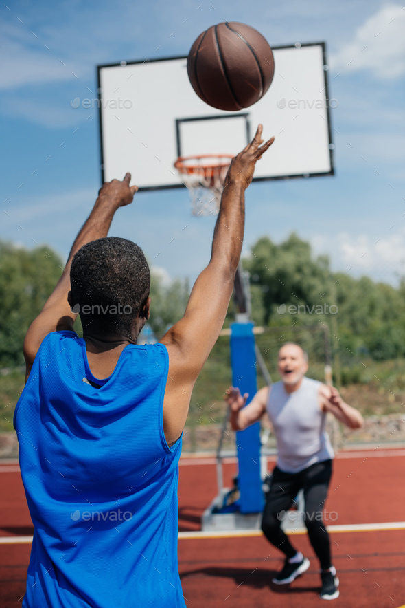 multiracial elderly men playing basketball together on playground on ...