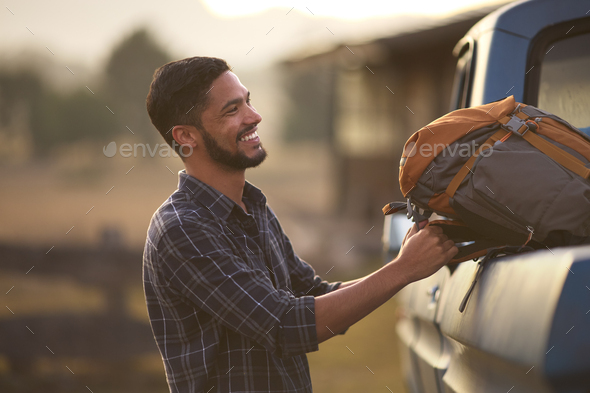 Man Loading Backpack Into Pick Up Truck For Road Trip To Cabin In ...