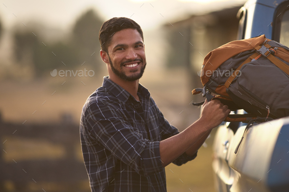 Portrait Of Man Loading Backpack Into Pick Up Truck For Road Trip To ...