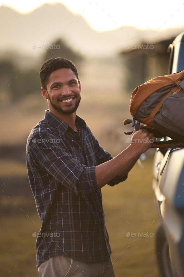 Portrait Of Man Loading Backpack Into Pick Up Truck For Road Trip To ...