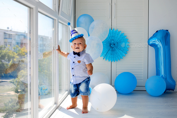 A little boy in the cap , stands near a pan-window, on his birthday. 1 ...