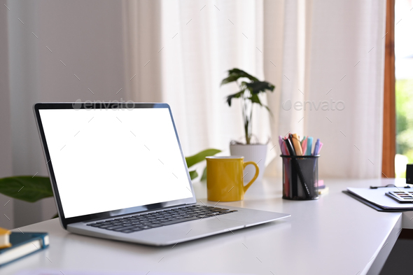 White office desk with laptop computer, coffee cup, potted plant and ...