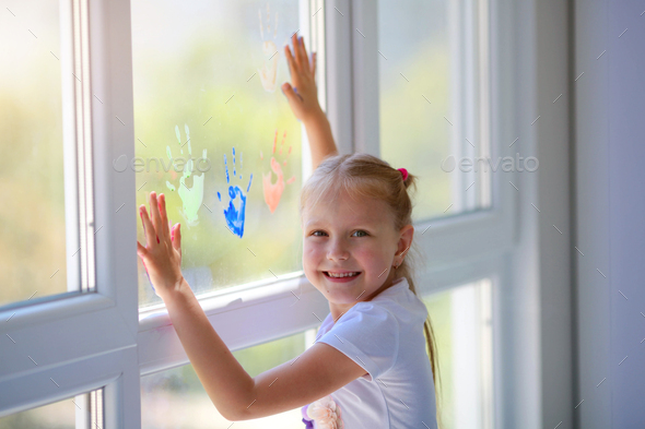 Children girl draw with palms on the window. Stock Photo by smile23