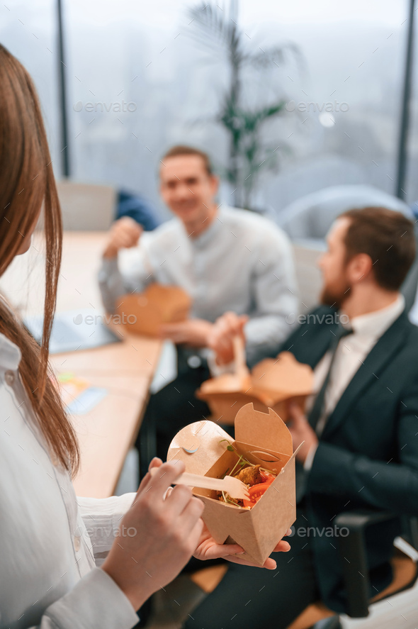 Close up view of meal. Group of coworkers are eating food from eco ...