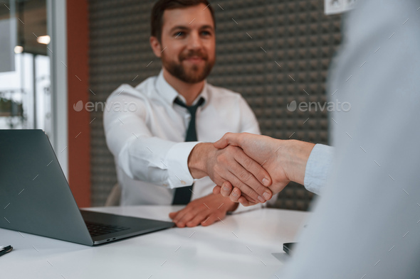 Making handshake, nice to meet you. Office workers are indoors by the ...