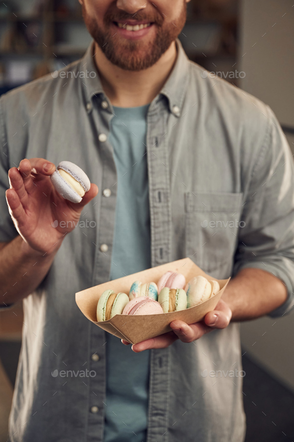 Holding and showing macaron. Man in casual clothes is holding sweets ...