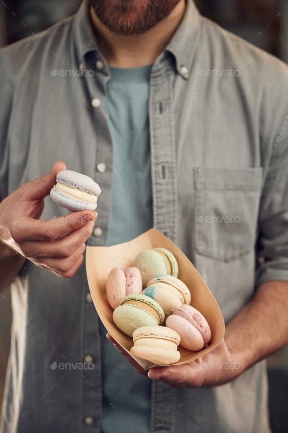 Man in casual clothes is holding macarons that are in the paper eco box ...