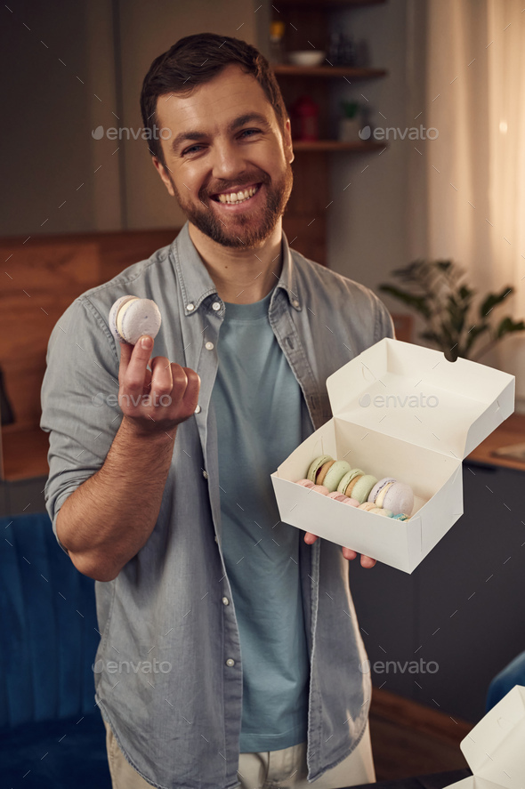 Holding and showing macaron. Man in casual clothes is holding sweets ...