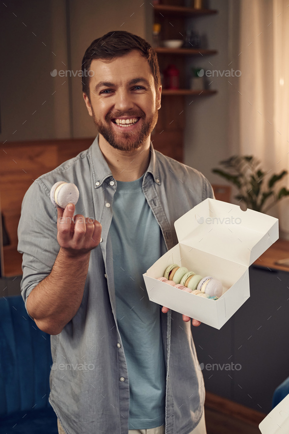 Holding and showing macaron. Man in casual clothes is holding sweets ...