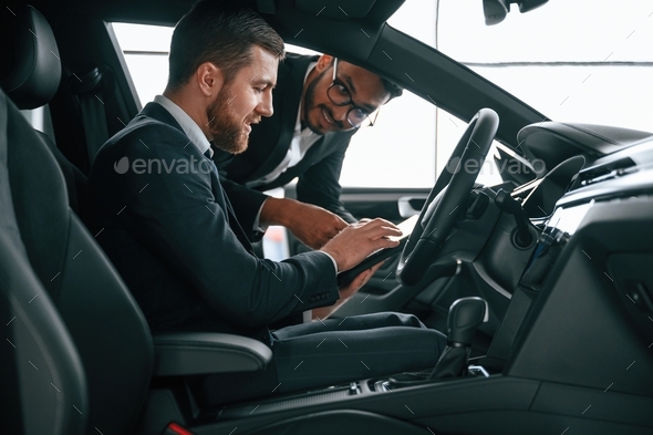 Side view. Man showing automobile interior to the customer Stock Photo ...