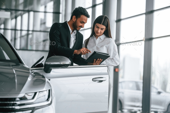 Man in formal clothes is consulting woman about the automobile in the ...