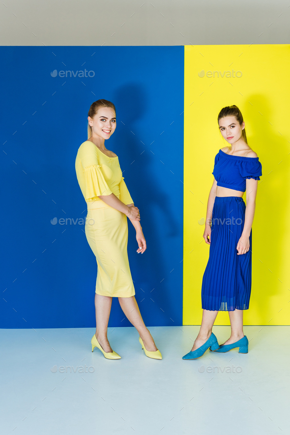 Female fashion models in blue and yellow outfits posing on matching ...