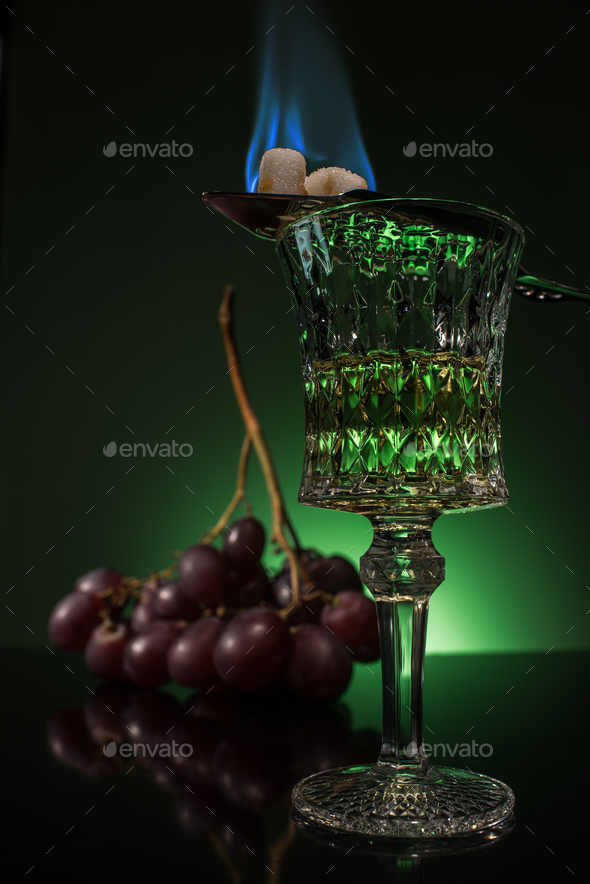 lead glass of absinthe with branch of grapes and burning sugar on spoon ...