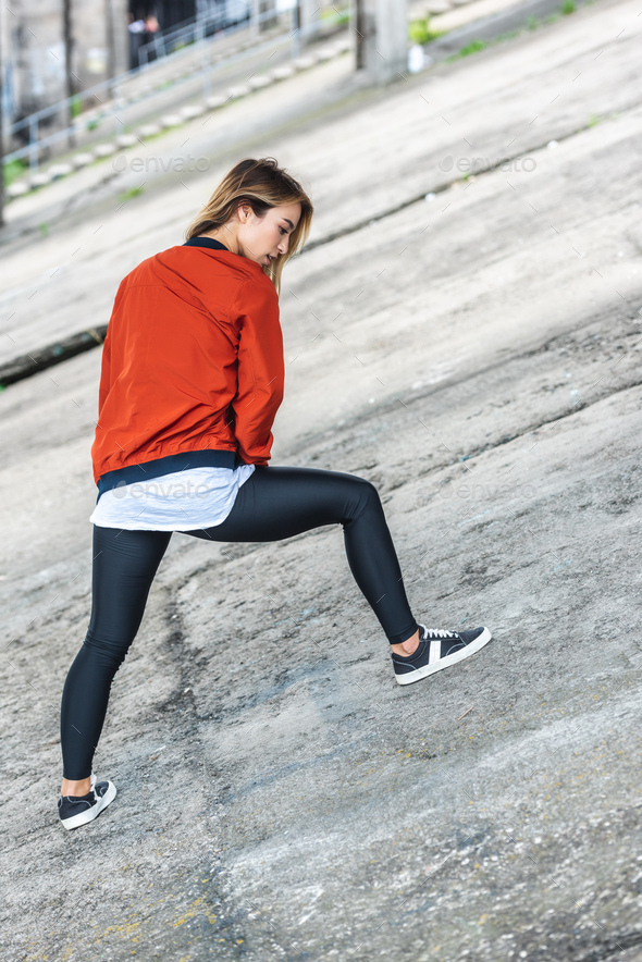 side view of young asian stylish female urban dancer dancing at city ...