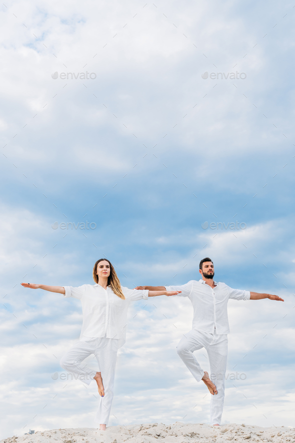 bottom view of young couple practicing yoga in tree pose (Vrksasana) on ...