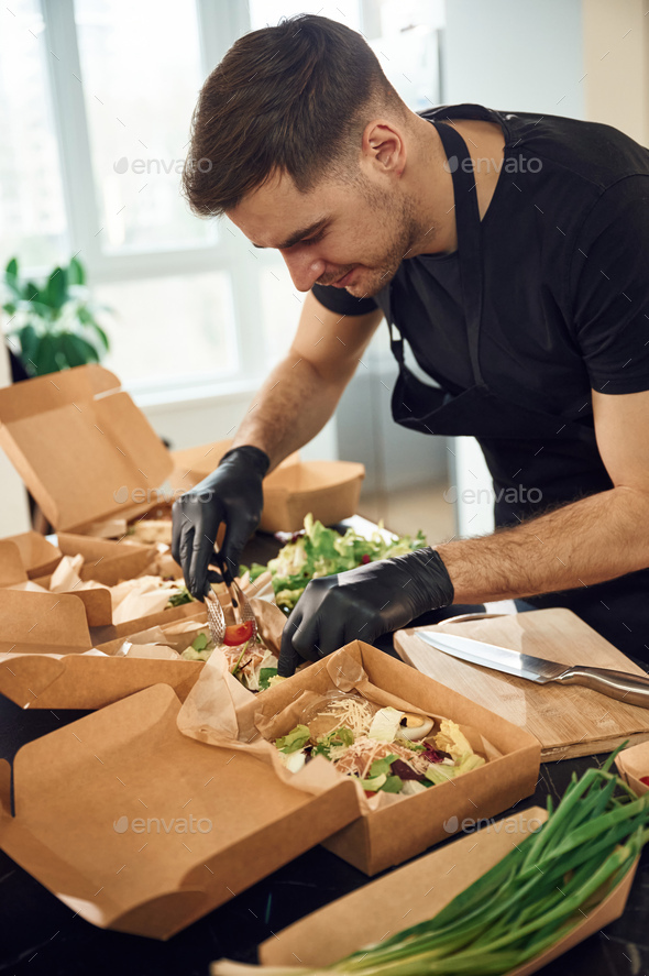 Vegetables added to the burgers. Man is packing food into the paper eco ...