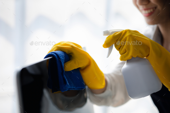 Person cleaning room, cleaning worker is using cloth to wipe computer ...