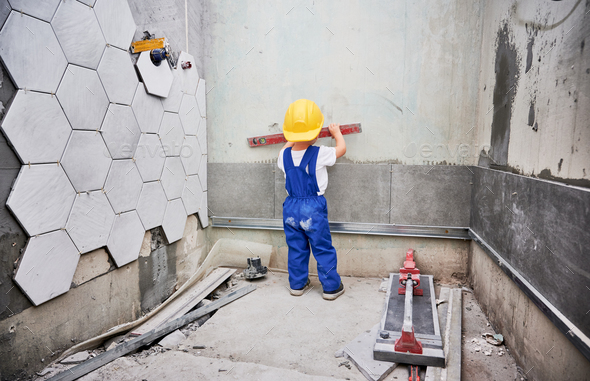 Child construction worker checking wall with spirit level tool. Stock ...