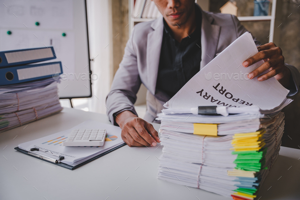 work from office A businessman works a bunch of paper files to find ...