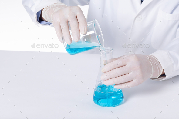 Closeup of a scientist experimenting with blue toxic substances in ...