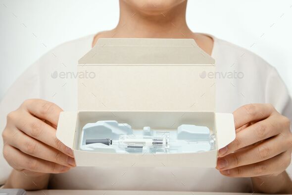 Closeup of female hands holding a package box with a syringe of healing ...