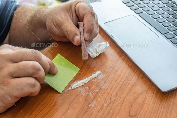 Closeup of a male hand preparing a cocaine line on the desk of the ...
