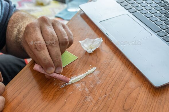 Closeup of a male hand preparing a cocaine line on the desk of the ...