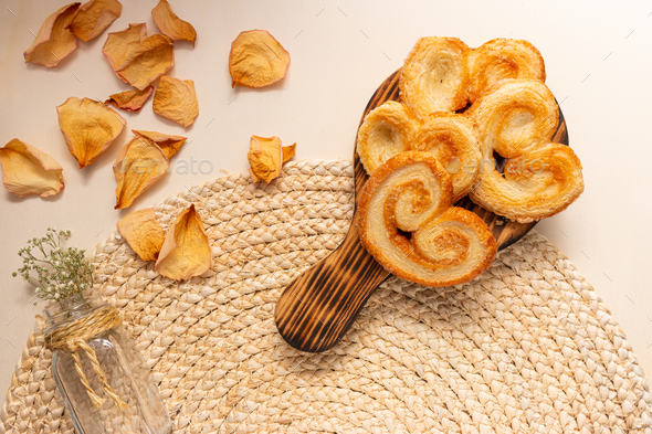 Flat lay of a glass vase with flowers, a board with palmier cookies ...