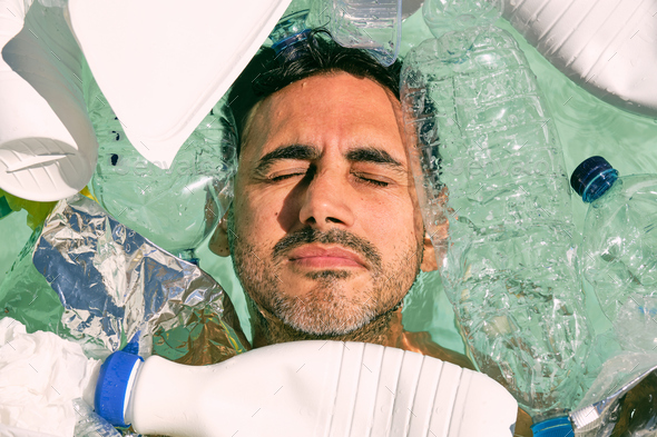 man in the water with his face up surrounded by plastic bottles ...