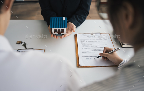 real estate agent or salesman holds a house model to describe the ...