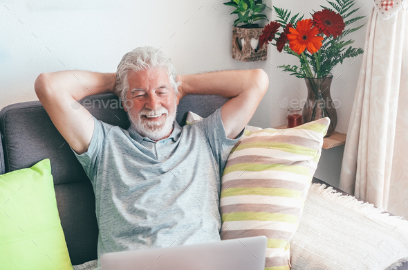 Senior relaxed man smiling sitting on sofa using laptop, grandfather ...