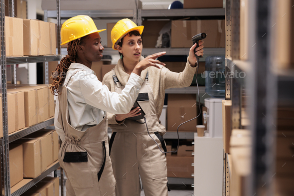 African american and caucasian warehouse operators scanning boxes ...