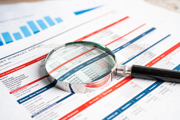 Magnifying glass and calculator on spreadsheet and charts graphs paper ...