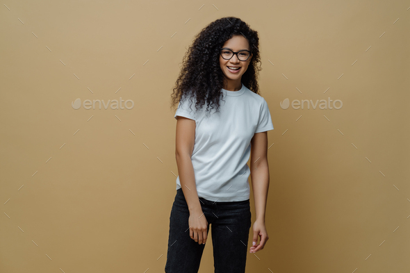 Smiling dark skinned young woman with glad face expression, wears ...