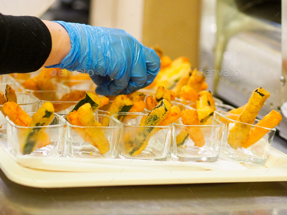 chef hand wearing gloves preparing fried snacks to serve at finger food ...