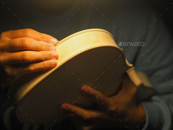 violin maker luthier hands roughing the edges of a raw blank violin ...