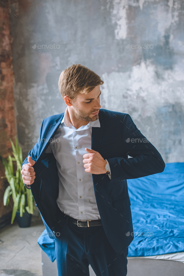 serious businessman putting on jacket in bedroom at home Stock Photo by ...