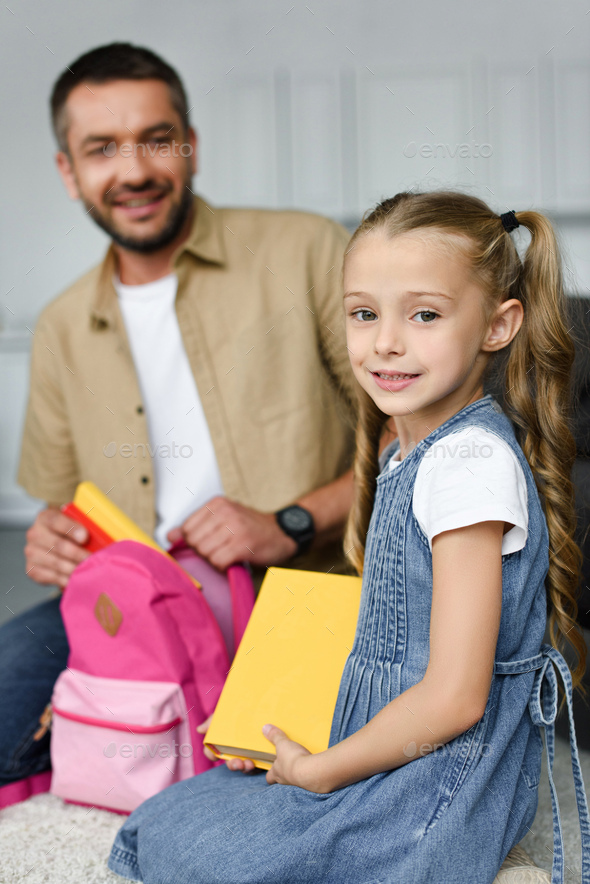 selective focus of daughter and father packing backpack for first day ...