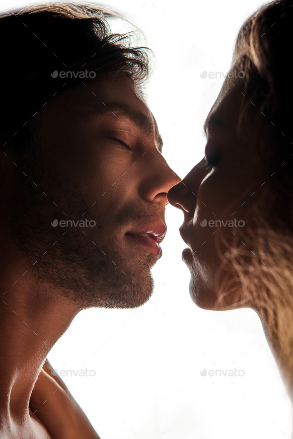 side view of couple kissing while standing face to face, isolated on ...