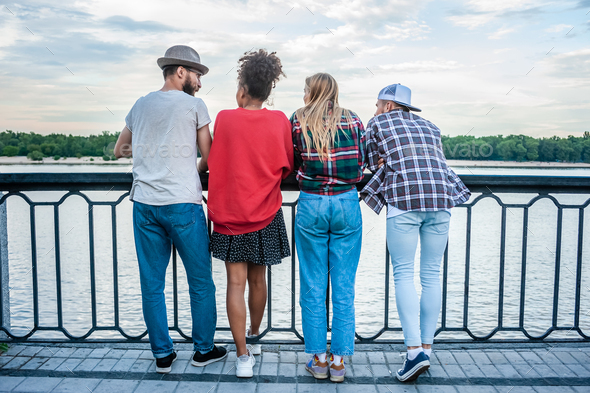 back view of four young multiethnic friends standing together on ...